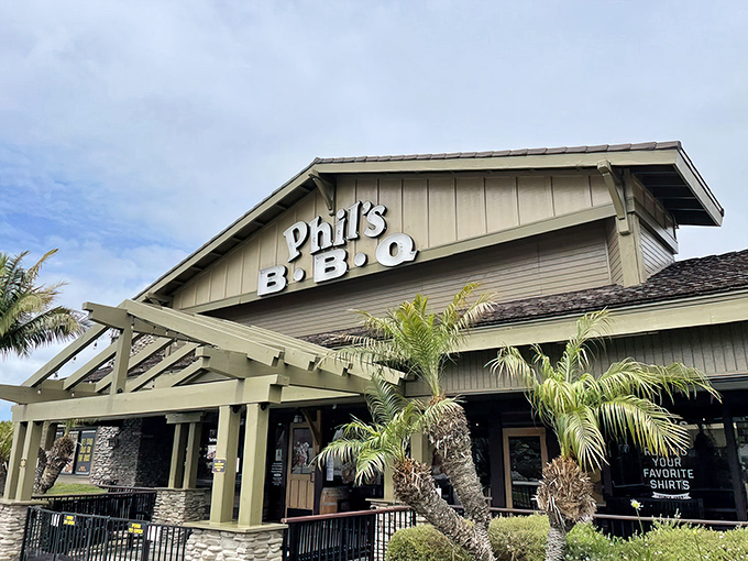 The California sun plays peekaboo with Phil's BBQ's iconic façade, where palm trees stand guard over what might be San Diego's most aromatic parking lot.