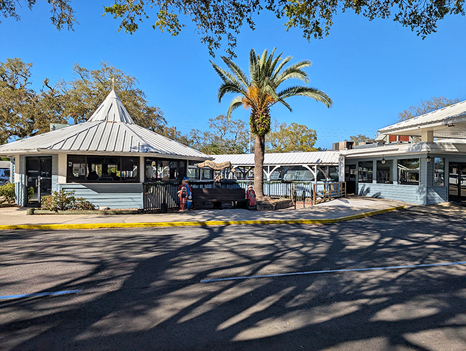 Florida sunshine casts dramatic shadows across this unassuming seafood temple, where palm trees stand guard over decades of delicious memories.