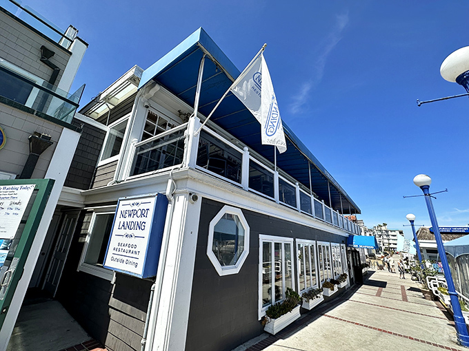 The distinctive navy-blue awning and nautical architecture of Newport Landing Restaurant stands as a beacon for hungry harbor-goers seeking seafood salvation.