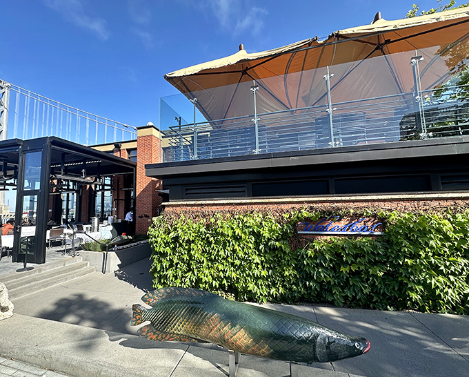 Waterbar's exterior is architectural poetry &ndash; where modern design meets maritime charm, complete with that whimsical fish sculpture standing guard like an aquatic bouncer.