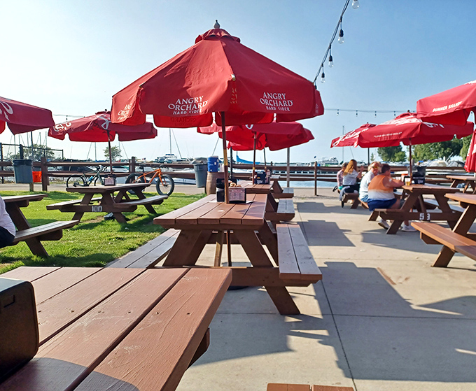 Paradise found! Red umbrellas dot the lakeside patio where wooden picnic tables invite you to linger as boats bob gently in the background.
