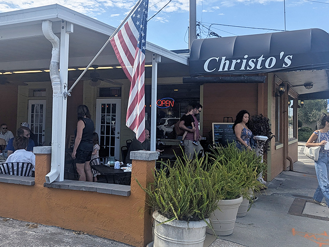 The welcoming orange facade of Christo's Cafe stands as a beacon of breakfast hope, American flag proudly waving to hungry Orlando locals.