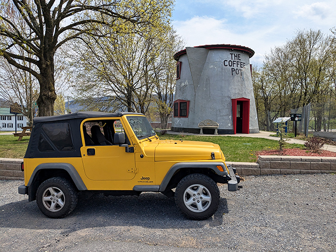 The ultimate roadside pick-me-up! Bedford's 18-foot Coffee Pot stands proudly alongside a bright yellow Jeep, proving everything's better supersized.