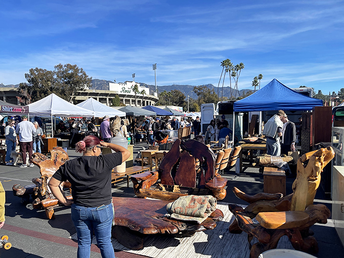 The iconic Rose Bowl Stadium backdrop transforms into treasure hunter paradise, where handcrafted wooden furniture meets California sunshine under a perfect blue sky.