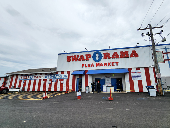 The red and white striped exterior of Swap-O-Rama stands like a carnival of commerce, promising treasures within for the intrepid bargain hunter.
