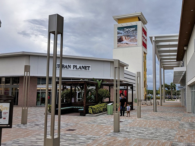 The iconic Tanger Outlets entrance welcomes shoppers with palm trees and modern architecture, promising retail adventures under the Florida sky.