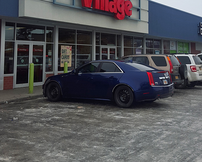 The iconic red Value Village sign beckons like a lighthouse for bargain hunters, promising treasures within those sliding glass doors.