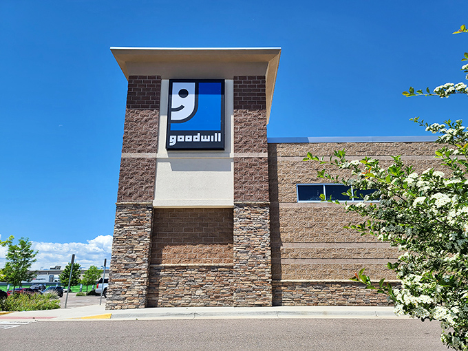 That iconic blue smile against Colorado's bluer sky &ndash; Goodwill's exterior promises treasure hunting adventures before you even step inside.