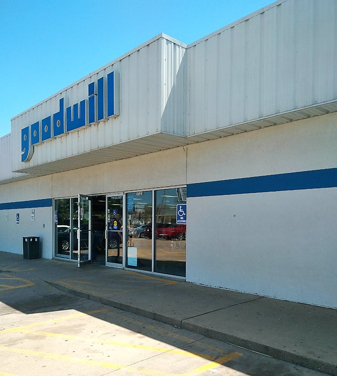 The iconic blue and white Goodwill sign beckons like a lighthouse for treasure hunters. Kansas sunshine makes even bargain hunting feel like a vacation.