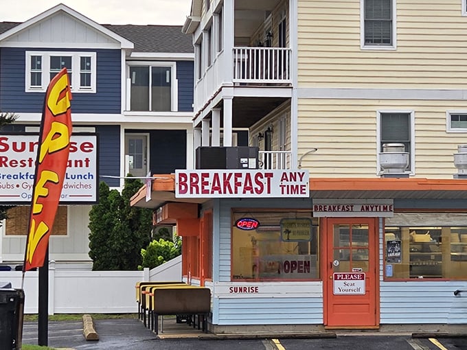 The bright orange door and "BREAKFAST ANY TIME" sign are like culinary bat signals to hungry beachgoers. No cape required, just an appetite.