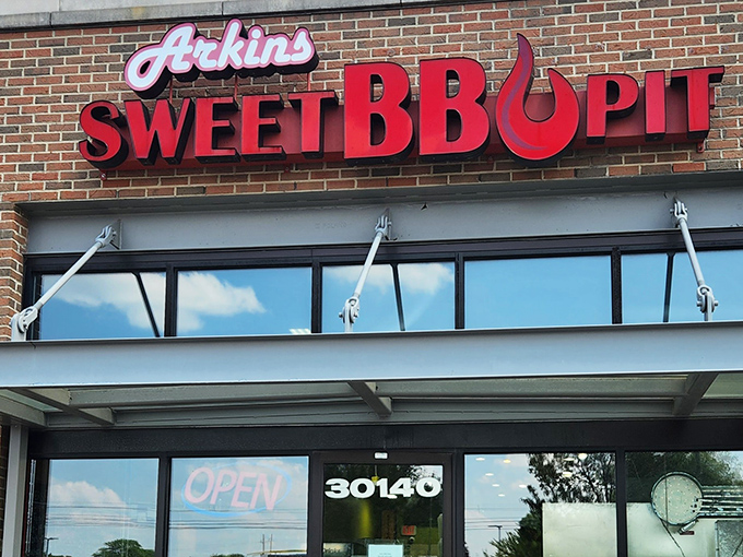 The fiery red signage of Arkins Sweet BBQ Pit stands out against brick like a beacon to hungry travelers. No fancy frills needed when the food does all the talking.