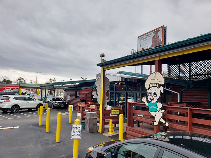 The log cabin exterior of Rib & Loin welcomes hungry travelers with its cheerful chef mascot and yellow safety poles standing guard like sentinels protecting barbecue treasure.