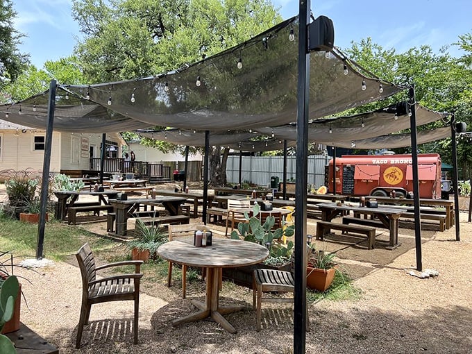 Shade canopies and string lights transform this rustic outdoor space into a barbecue oasis. It's where strangers become friends over the universal language of smoked meat excellence.
