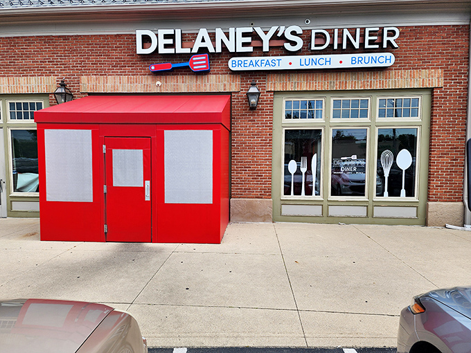 The iconic red entrance booth at Delaney's Diner stands like a cheerful sentinel, promising comfort food treasures within this brick Columbus landmark.