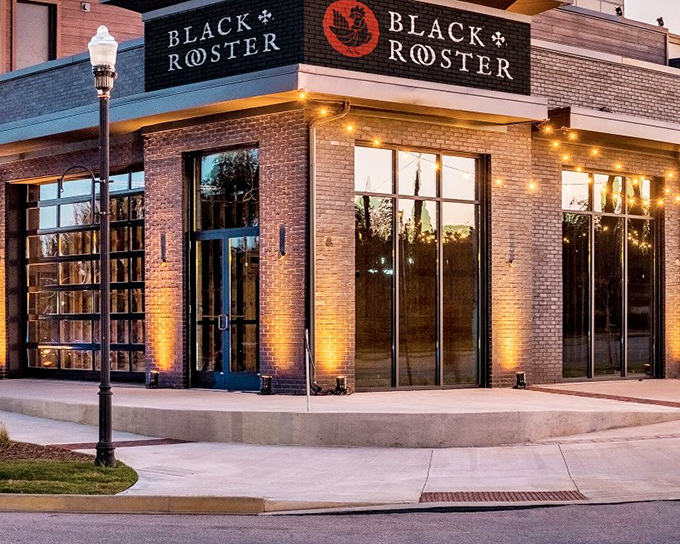 The brick facade of Black Rooster glows warmly at dusk, its bold signage promising culinary adventures within. A modern beacon for food lovers in West Columbia.