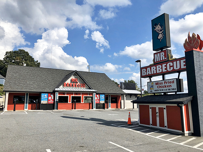 The red-trimmed roadside temple to smoked meat stands proudly against Carolina blue skies, its vintage sign a beacon to barbecue pilgrims since 1962.
