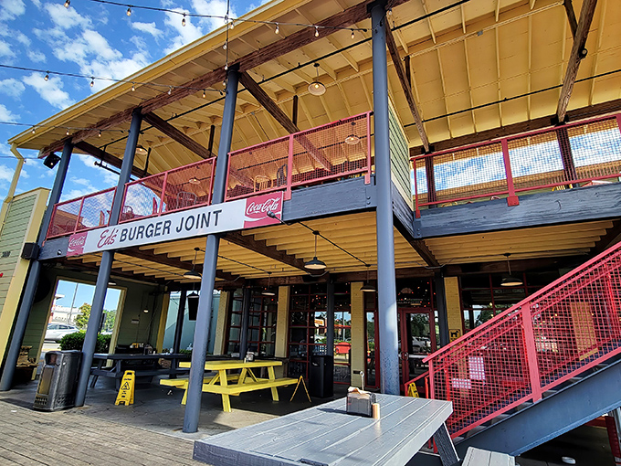 The bright yellow exterior of Ed's Burger Joint stands like a beacon of burger hope in Hattiesburg, complete with cheerful red railings and outdoor seating.
