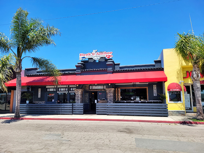 The bright red awning of Hook & Anchor beckons like a seafood siren against the California sky, promising maritime treasures within those unassuming walls.