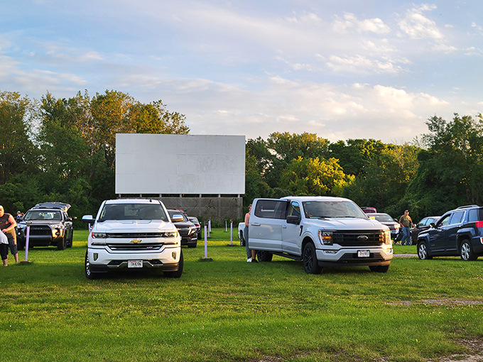 Cars lined up like eager moviegoers at their high school reunion, facing the blank canvas that will soon burst into cinematic life.