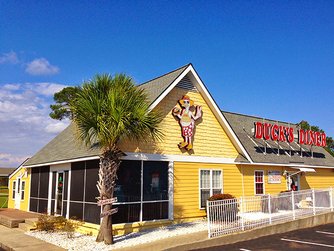 The sunshine-yellow exterior of Duck's Diner stands out like a beacon of breakfast hope, complete with a cartoon duck mascot that seems to say, "Come on in, the pancakes are fine!"