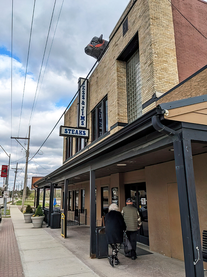 The unassuming brick exterior of Jess & Jim's, complete with its iconic steer sign, promises authentic steakhouse magic within. No pretension, just perfection.