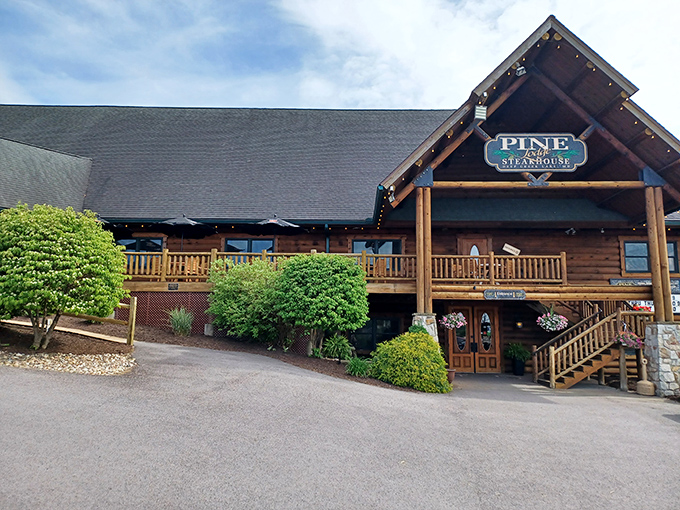 The grand log cabin exterior of Pine Lodge Steakhouse beckons hungry travelers with its rustic charm and twinkling lights. Mountain dining at its most inviting.