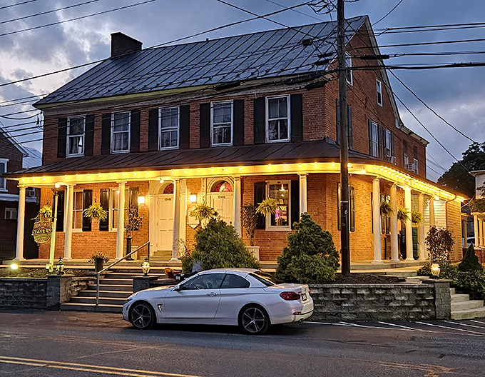 Twilight transforms this historic brick tavern into a beacon for hungry travelers, its warm porch lights promising comfort food salvation after a long day's journey.
