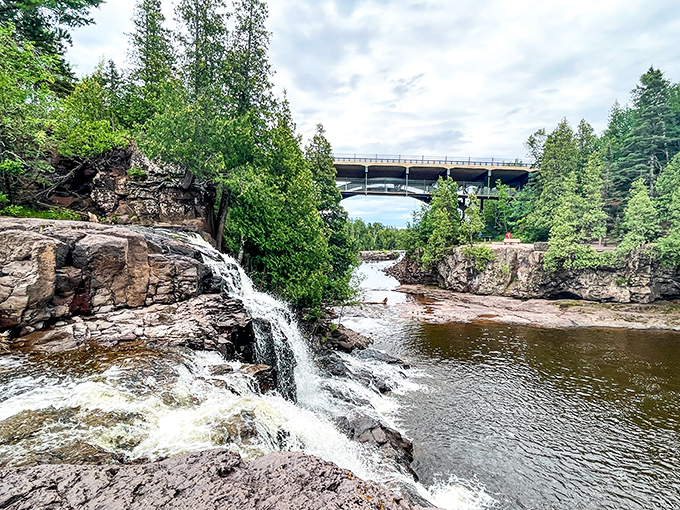 Nature's perfect postcard moment: cascading waters frame the Highway 61 bridge, creating that rare scene where human engineering complements rather than competes with natural splendor.