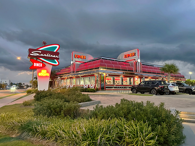 The neon-lit paradise of Sunliner Diner glows against the Alabama twilight, a chrome-clad beacon promising comfort food and nostalgia in equal measure.