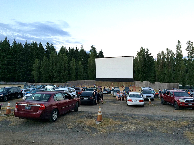 Cars gather under the twilight sky, their headlights dimming as the massive screen awaits its moment to transport everyone to another world.