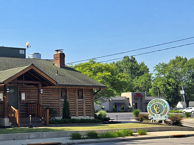 A green "Steakhouse" sign anchors the Cabin Club's roadside presence, where suburban Cleveland meets mountain lodge aesthetics in delicious harmony.