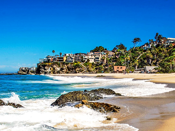 Paradise found! The golden crescent of 1000 Steps Beach stretches beneath luxury homes perched on sandstone cliffs, nature's perfect balancing act.