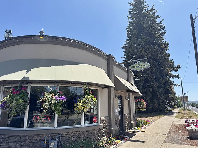 The curved facade of Mirror Lake Diner welcomes hungry travelers with colorful flower baskets and that magical neon "OPEN" sign that promises delicious salvation ahead.