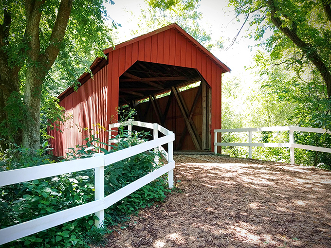 Like a crimson sentinel guarding the passage of time, Sandy Creek Covered Bridge welcomes visitors with its classic red siding and white fence&mdash;architectural poetry in rural Missouri.