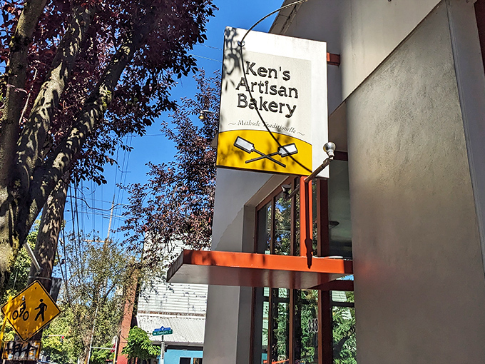 The unassuming storefront of Ken's Artisan Bakery stands like a beacon of hope for carb enthusiasts. That yellow sign promises more joy than most lottery tickets.