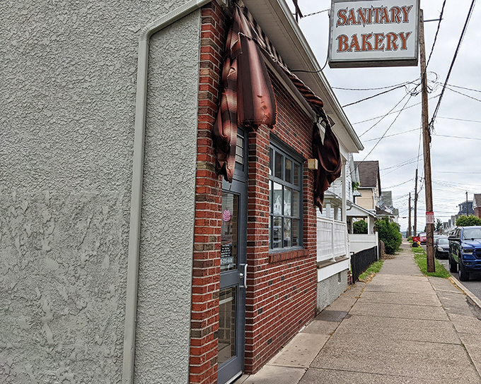 The unassuming brick exterior of Sanitary Bakery stands like a time capsule on this quiet Nanticoke street, its vintage sign promising sweet treasures within.