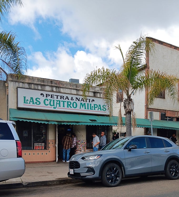 The turquoise-trimmed storefront of Las Cuatro Milpas stands like a beacon of culinary promise, palm trees swaying as if they too are waiting for those legendary rolled tacos.