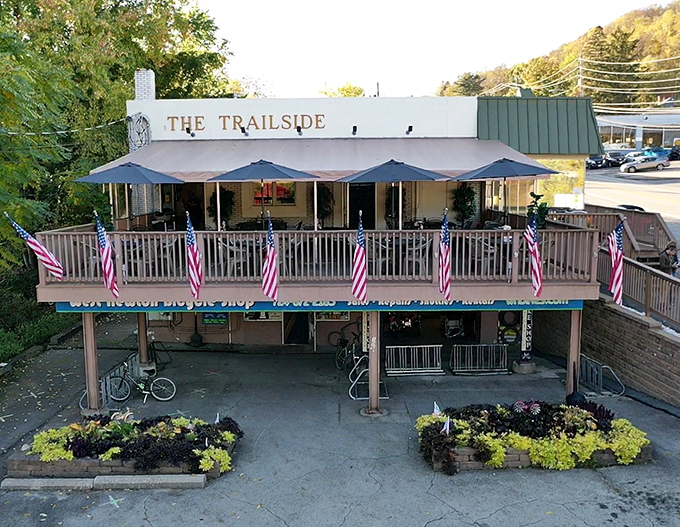The Trailside's welcoming facade, complete with American flags and a wooden deck, beckons hungry travelers like a culinary lighthouse on the Great Allegheny Passage.