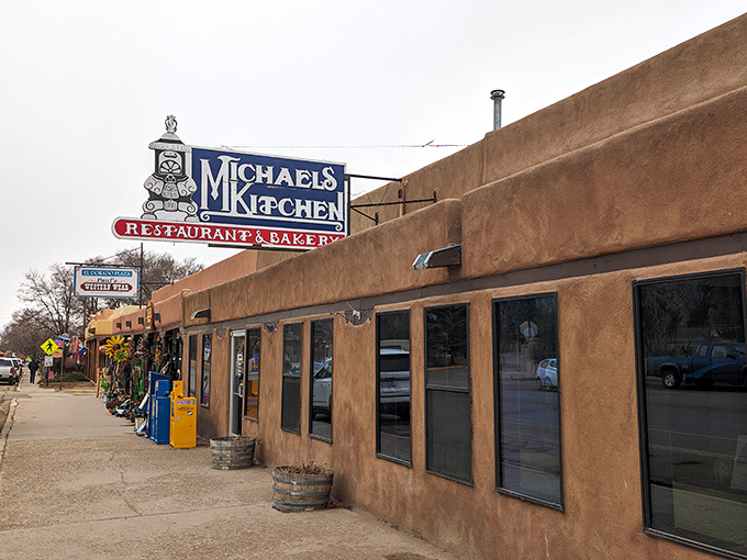 The classic adobe exterior of Michael's Kitchen stands as a beacon of breakfast hope on Taos's main street, complete with American flags proudly waving.