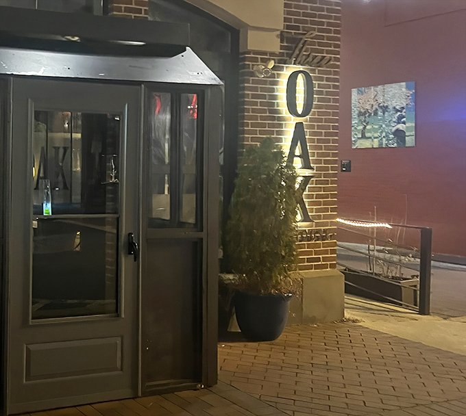 Evening at Three Oak transforms this entrance into a beacon of culinary promise, the illuminated sign a lighthouse guiding hungry souls to port.