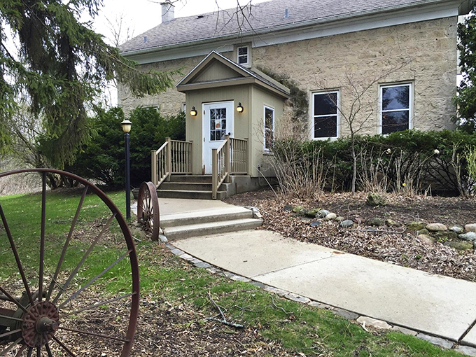 Stone walls meet wooden charm at this entrance, where an old wagon wheel nearby hints at the rustic treasures waiting inside.