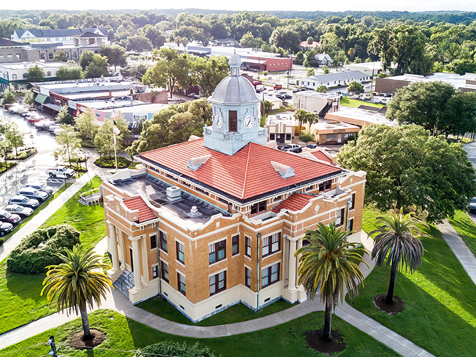 The historic Citrus County Courthouse stands like a proud sentinel, its copper dome gleaming in the Florida sunshine while palm trees frame this architectural gem.