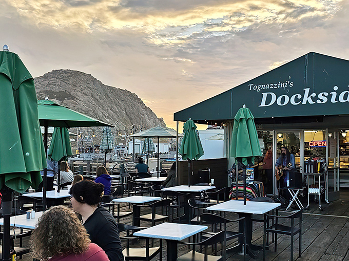 Morro Rock stands sentinel over Dockside Too's outdoor seating area, where every table comes with a million-dollar view that no interior designer could replicate.