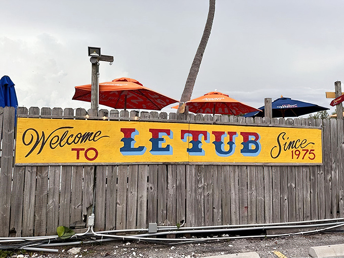 The weathered wooden fence with its cheerfully painted sign says it all: "Welcome to Le Tub." No pretension here, just Florida authenticity since 1975.