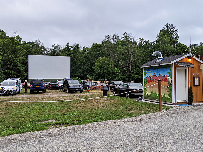 Cars gather at Four Brothers Drive-In, where the massive screen awaits twilight's embrace amid Amenia's lush greenery.