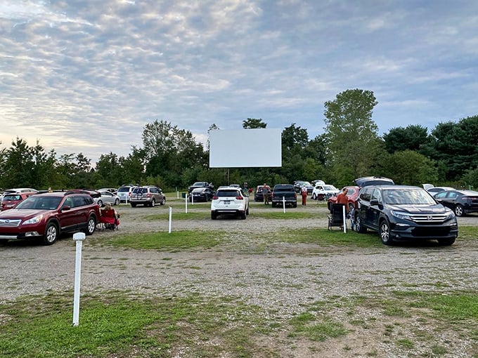Cars gather at Dependable Drive-In as dusk approaches, the blank screen waiting for nightfall's cinematic magic to begin.