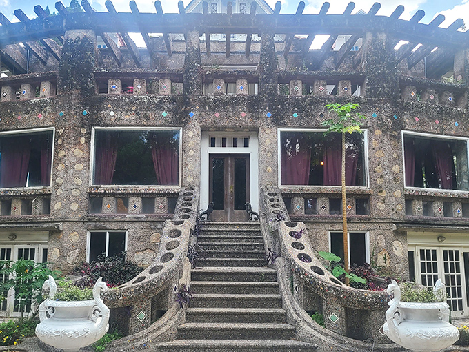 The grand entrance to Wonder House feels like the prologue to a fairytale, with its shell-studded facade and symmetrical staircase inviting exploration.