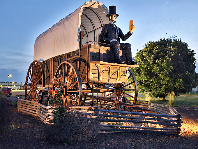 Honest Abe sits atop his supersized ride, proving that even presidents appreciate a good roadside spectacle. The wagon's massive wheels could flatten a compact car without breaking stride.