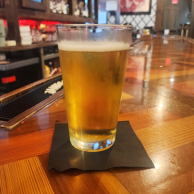 A perfectly poured beer catching the light like liquid amber. In the burger universe, this is the ideal co-pilot for your flavor journey.