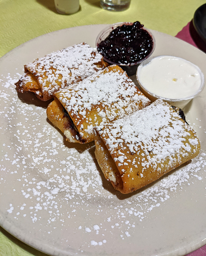 Blintzes dusted with powdered sugar, served with blueberry compote and sour cream. Sweet, tart, creamy—the holy trinity of breakfast dessert perfection.